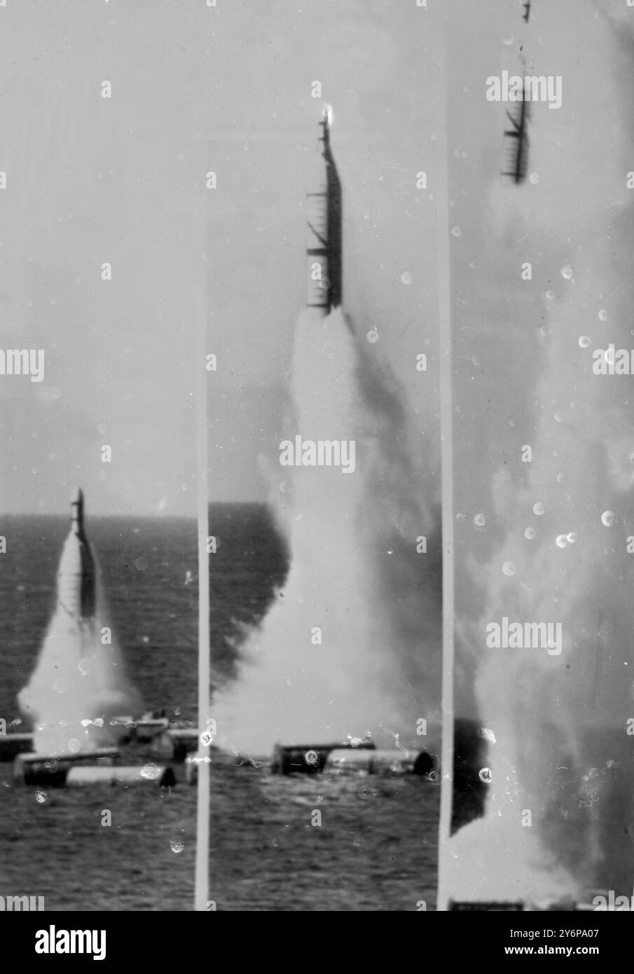 A bright yellow Polaris missile shoots out of the water off the island ...