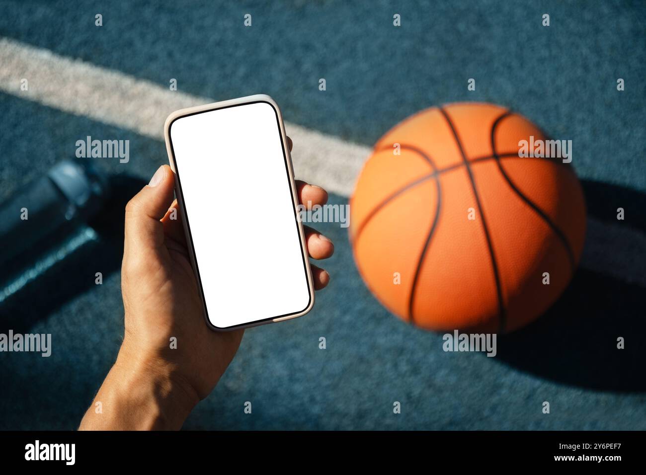 Smartphone in hands basketball player during game interval. Blank ...