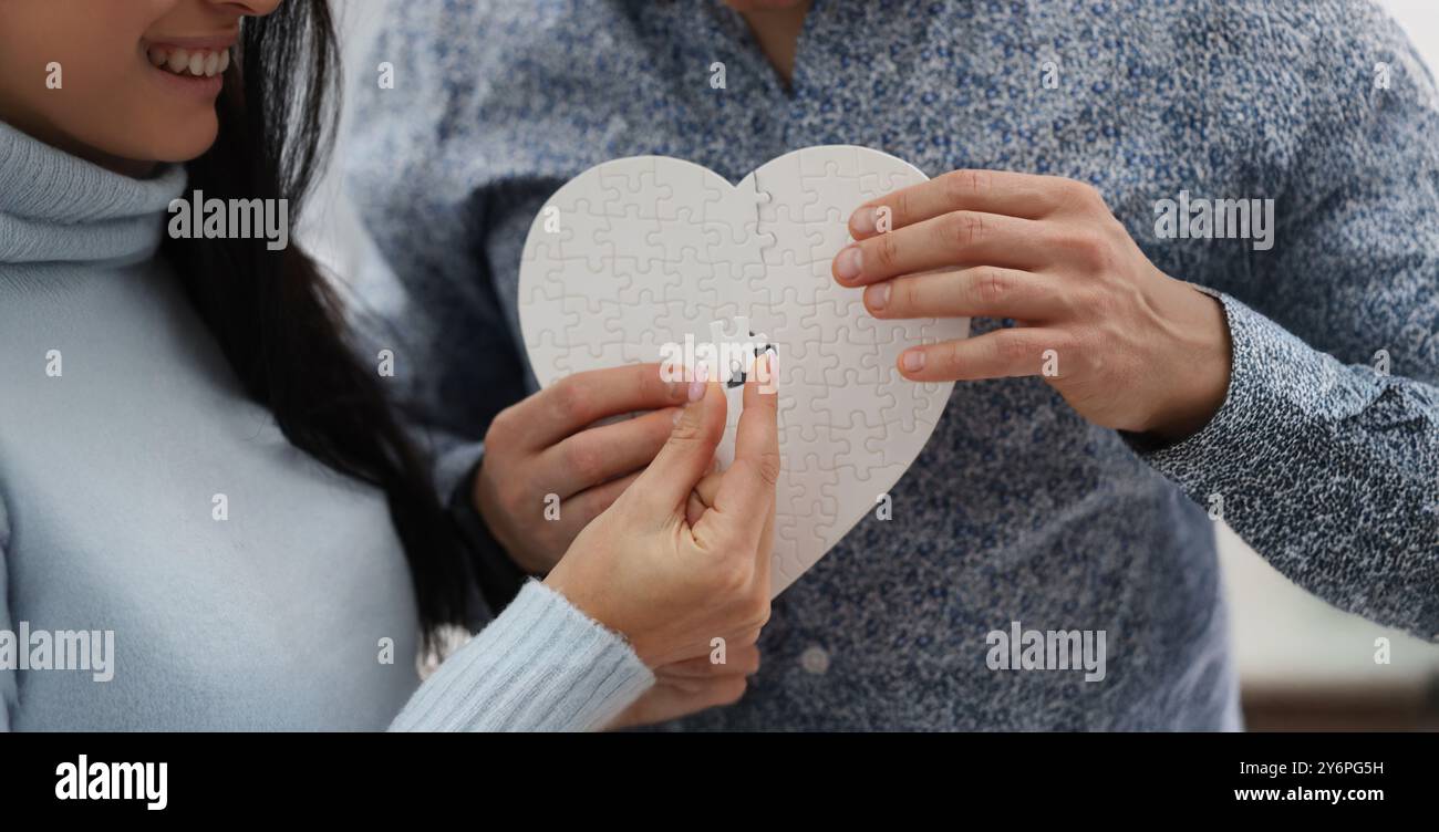 Woman and man fill empty space with missing piece of white heart puzzle ...