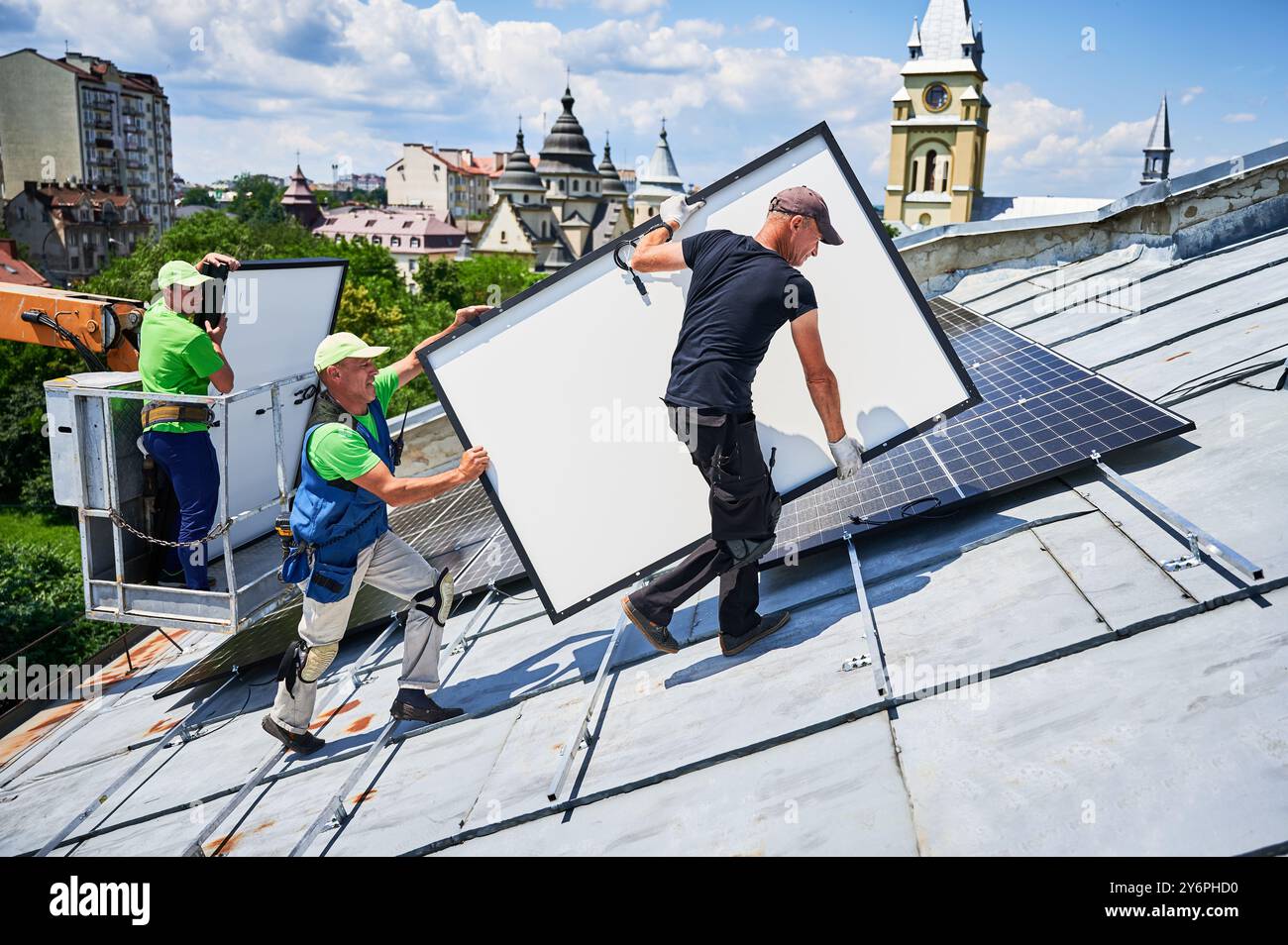 Workers building solar panel system on metal rooftop with assistance of ...