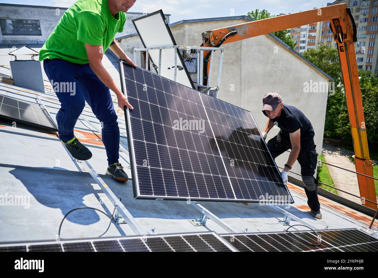 Workers building solar panel system on metal rooftop of house with ...