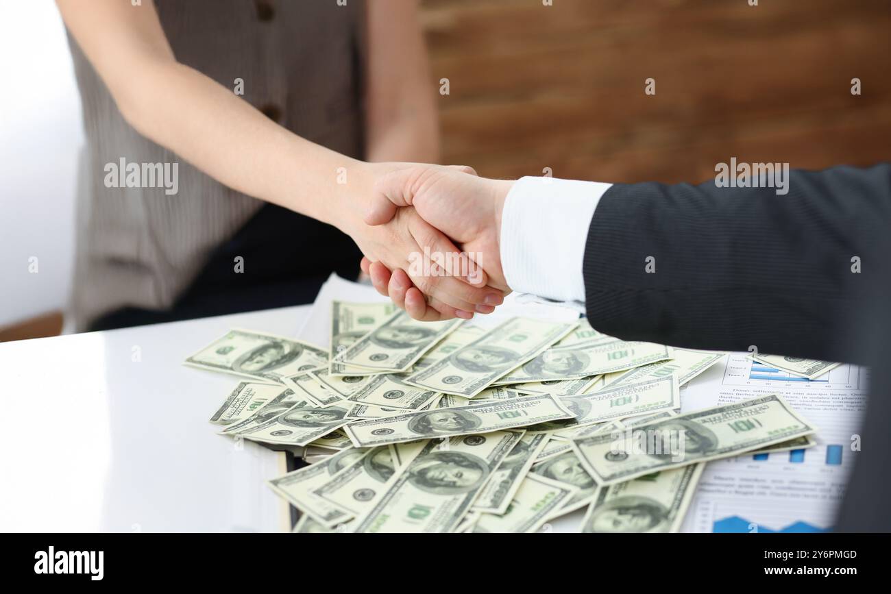 Man and woman shake hands over stack of dollars currency transaction of ...