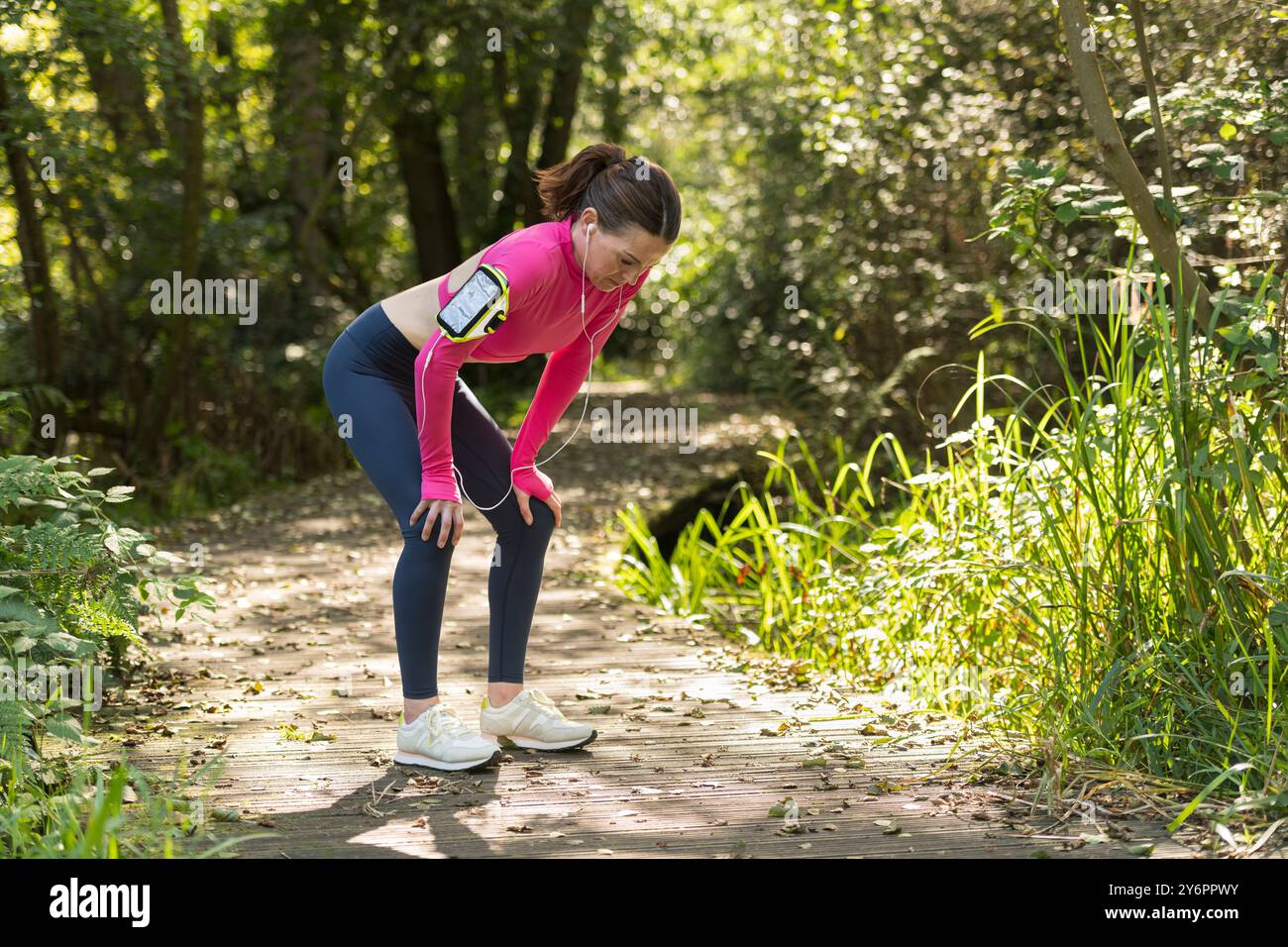 Sporty woman runner with her hands on her knees resting after exercise ...