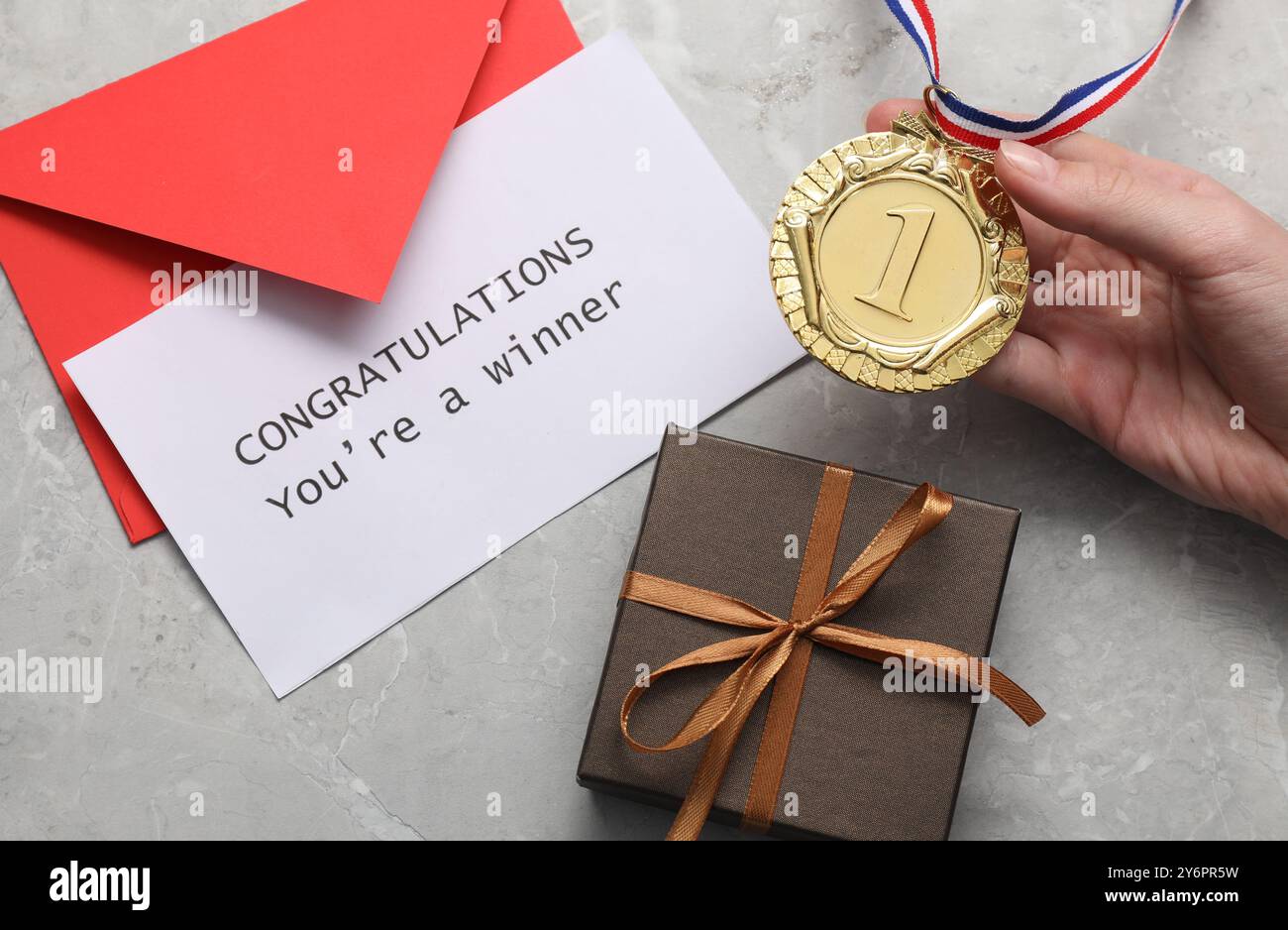 Woman holding golden medal, card with phrase Congratulations You`re ...