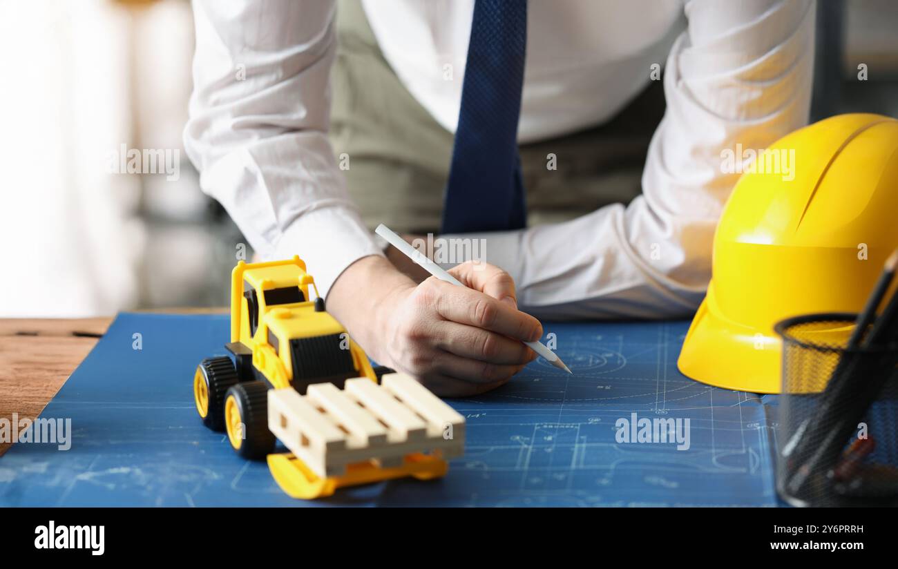 Male worker making corrections in construction planning with pencil ...