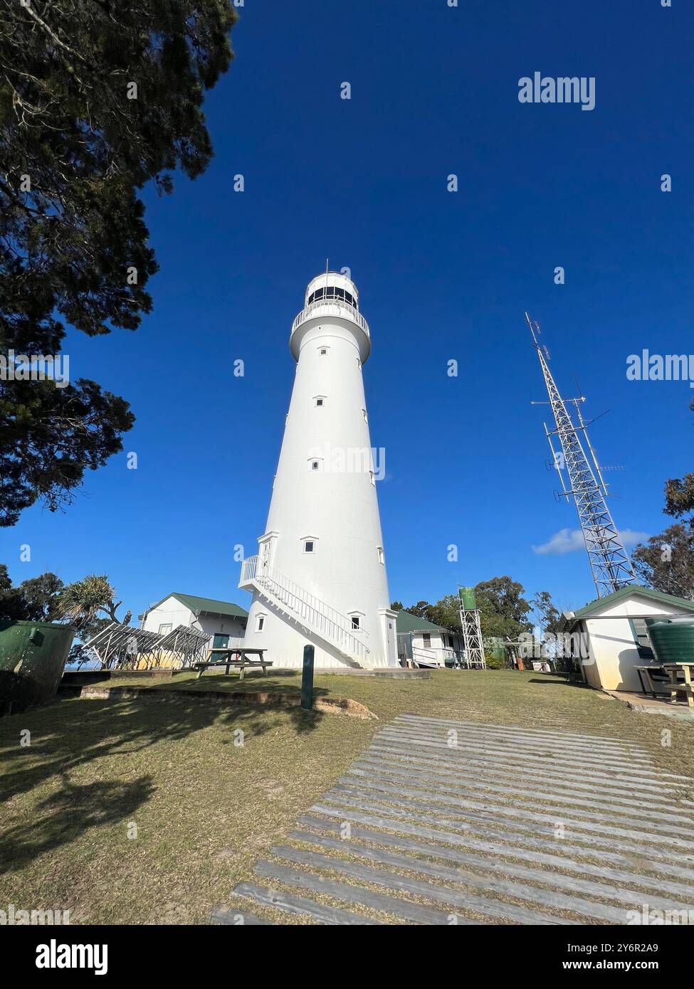 A vertical view of Sandy Cape Lighthouse, surrounded by buildings ...