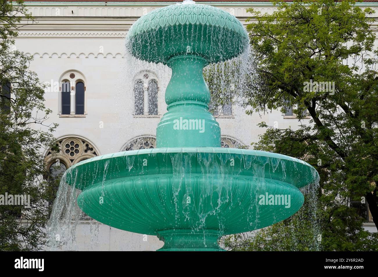 A vibrant turquoise fountain with cascading water in front of a ...