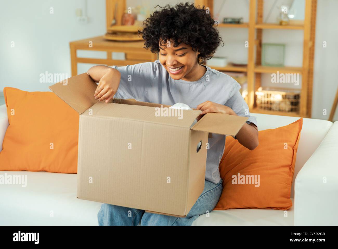 African girl unpacking delivery looking in box. Happy woman opening ...