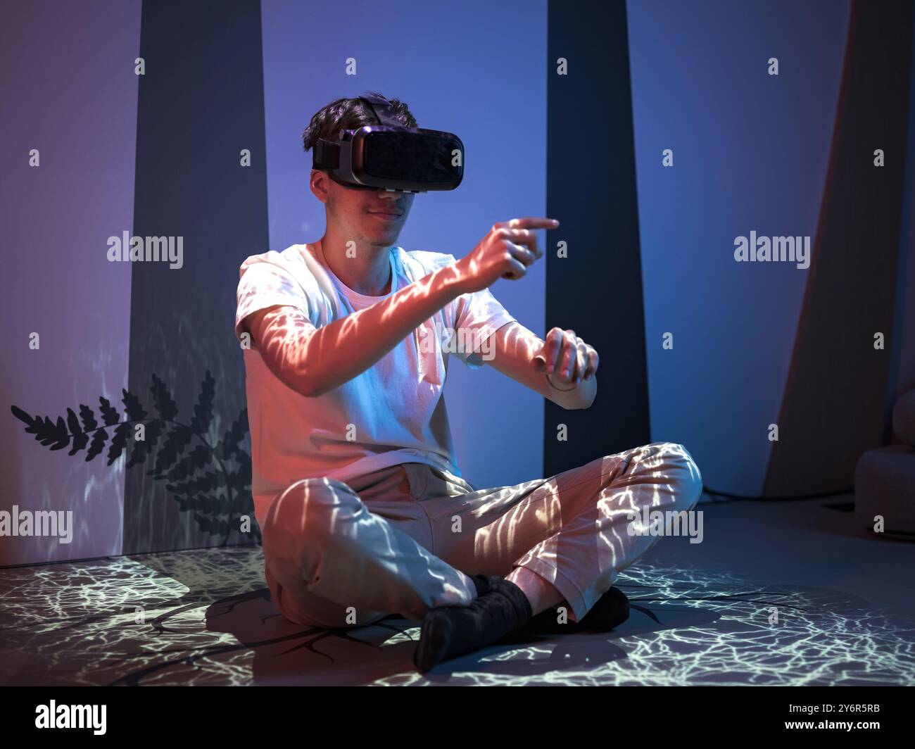Smiling teenage programmer boy sitting on the floor with a virtual ...