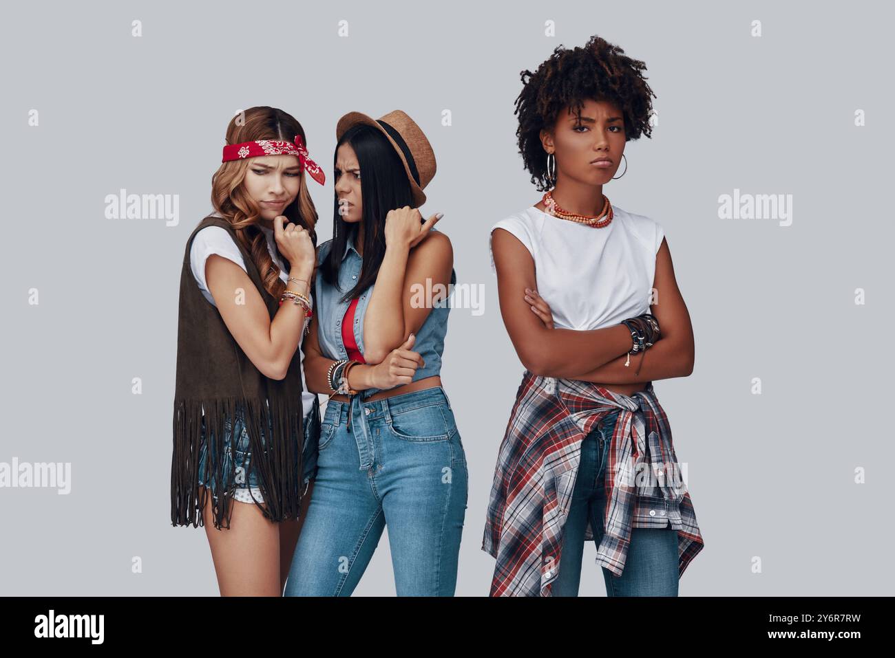 Two young women gossiping behind their girlfriends back while standing ...
