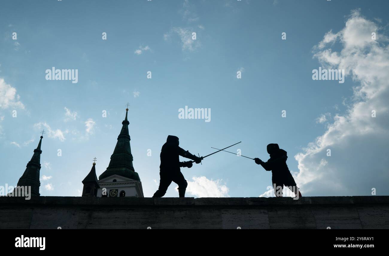 Two fencers dressed in black protective uniforms, helmets with face ...