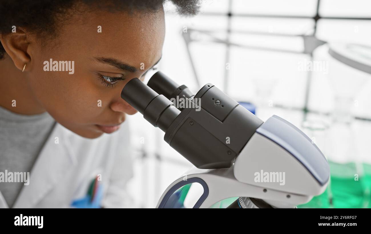 Focused african american woman using a microscope in a laboratory ...
