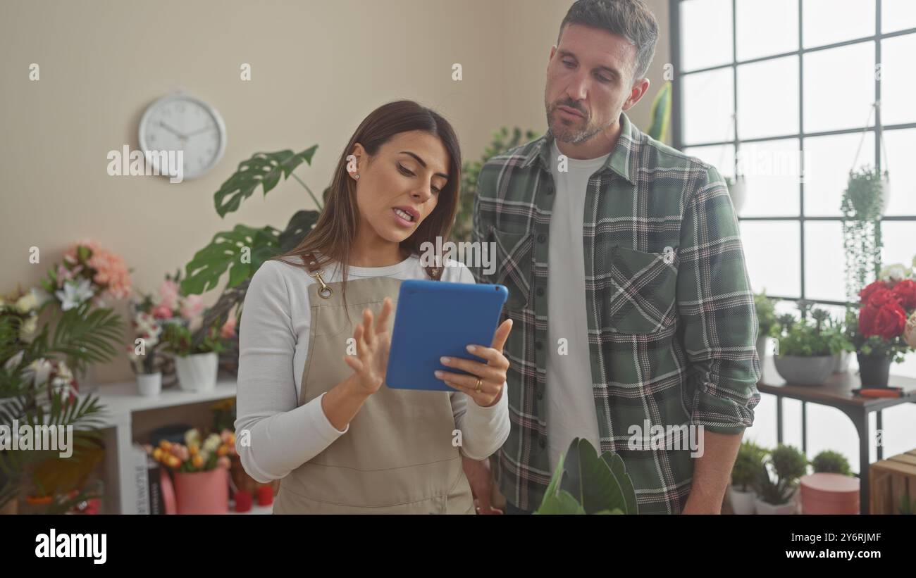 A man and woman, both florists, work together using a tablet inside a ...