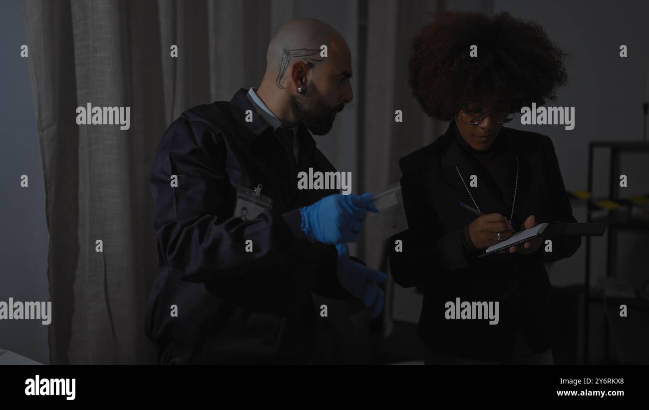 A man and woman investigating a dark indoor scene, examining evidence ...