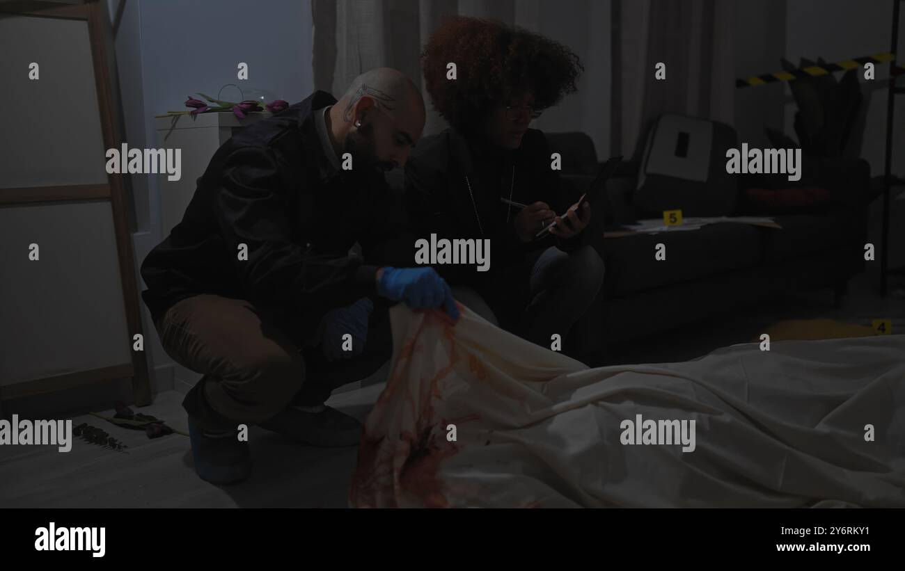 Investigators analyze evidence at an indoor crime scene in a dark ...