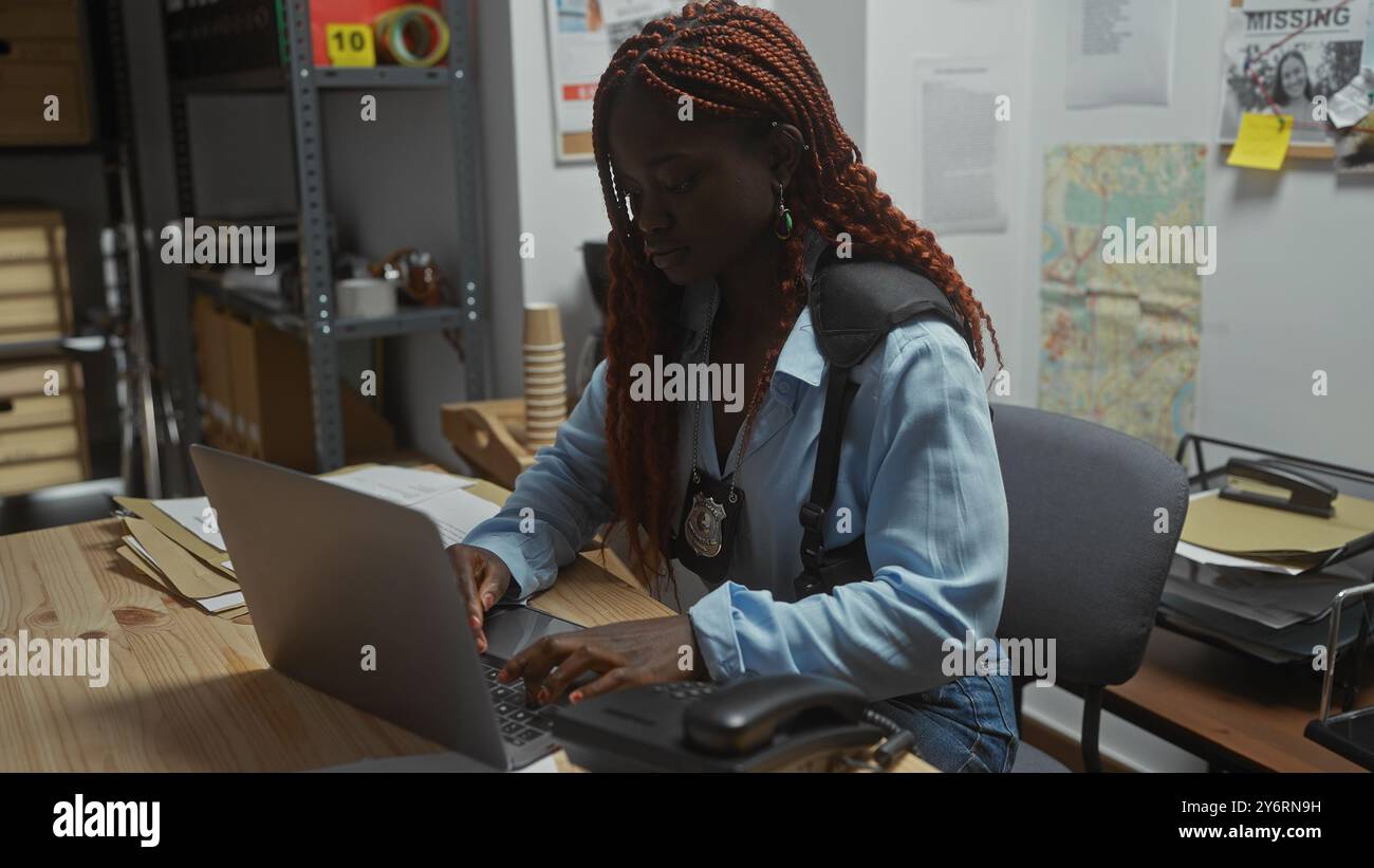 A professional young black woman detective working on a laptop in a ...