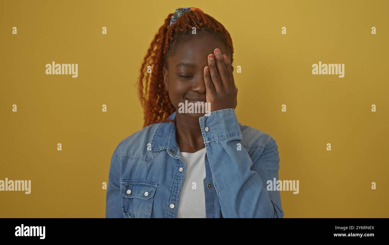 A young african american woman covers one eye with her hand against a ...
