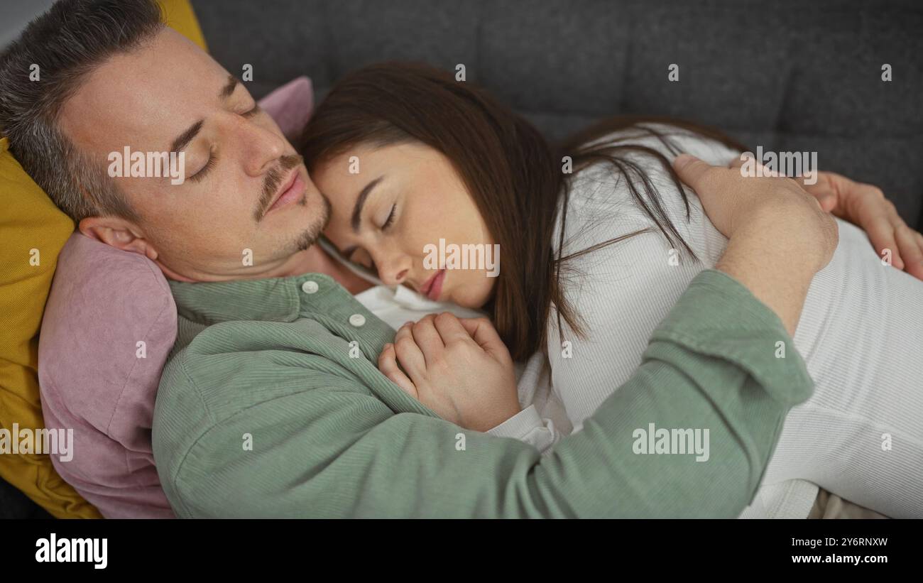 A loving couple embraces while napping together on a cozy sofa in a ...
