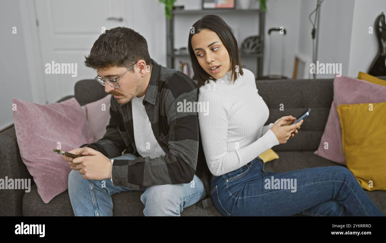 A woman secretly glances at a man's phone while they sit together on a ...