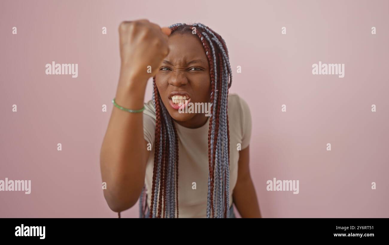 Angry african woman with braids against a pink background showing a ...