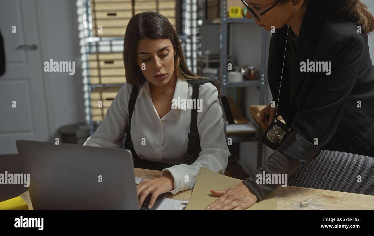 Two women investigators analyze evidence on a laptop inside an office ...