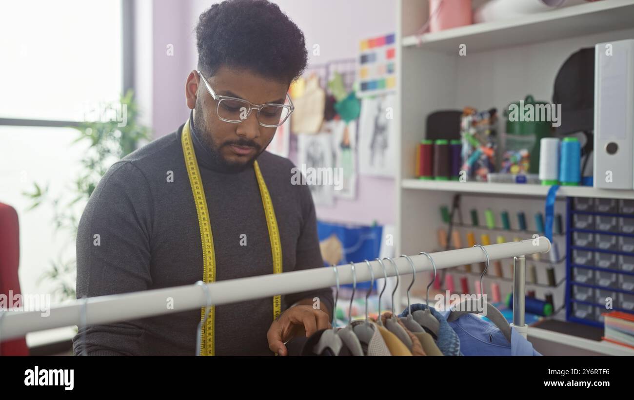 African american man with glasses in a tailor shop browsing fabric ...