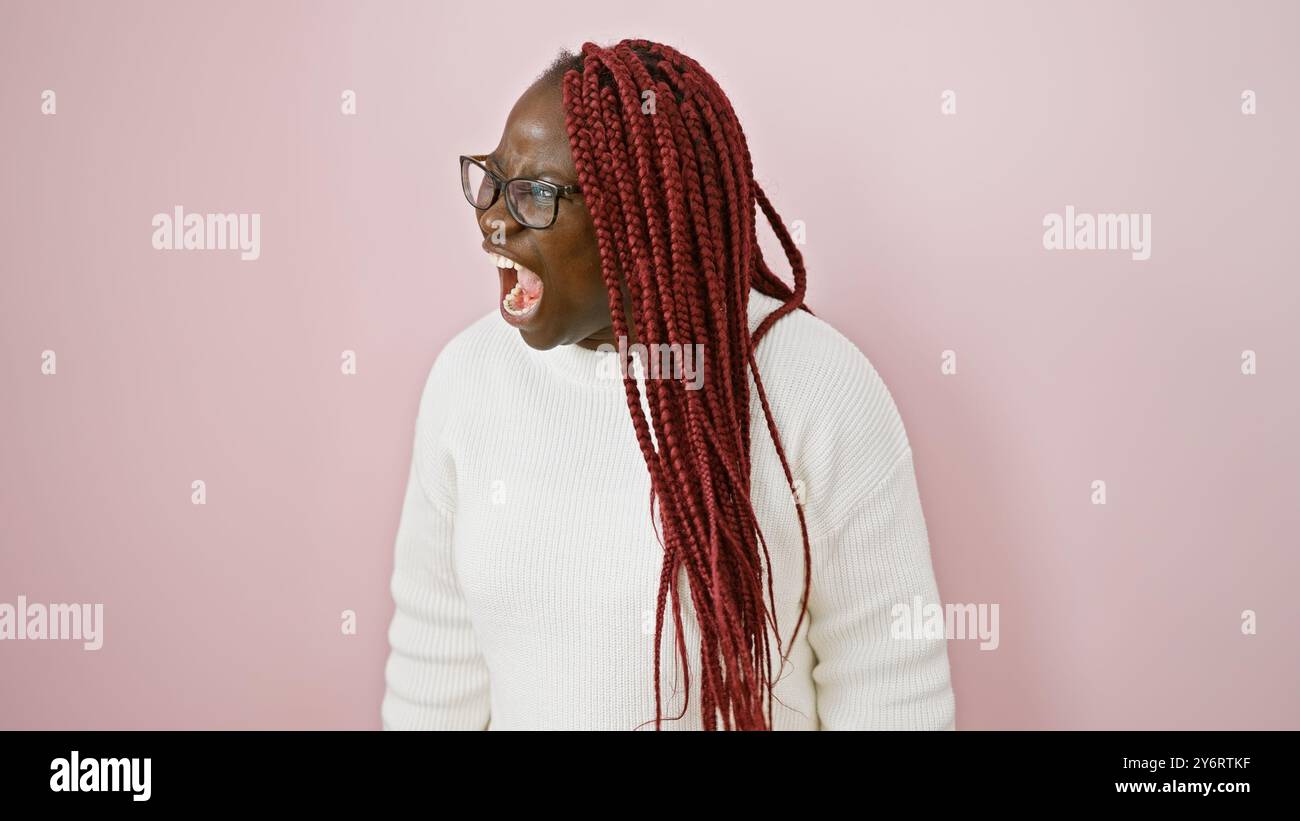 An african american woman with braids shouting over an isolated pink ...