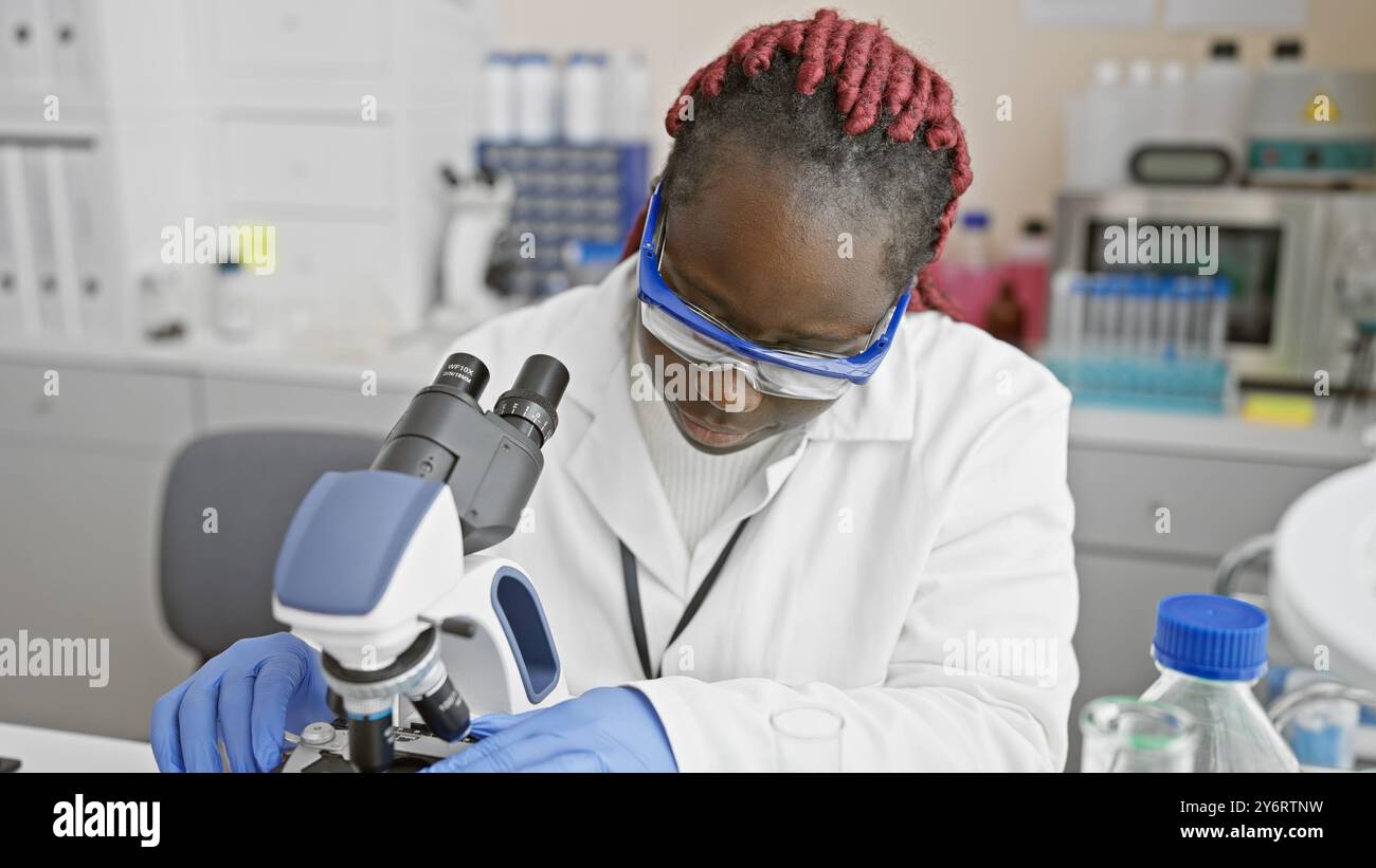 African-american woman with braids wearing lab goggles analyzes a ...