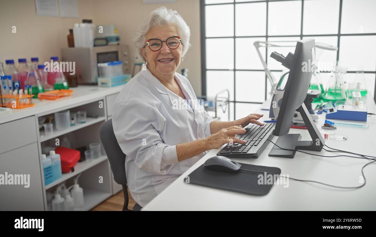 A smiling elderly woman scientist works on a computer in a modern ...
