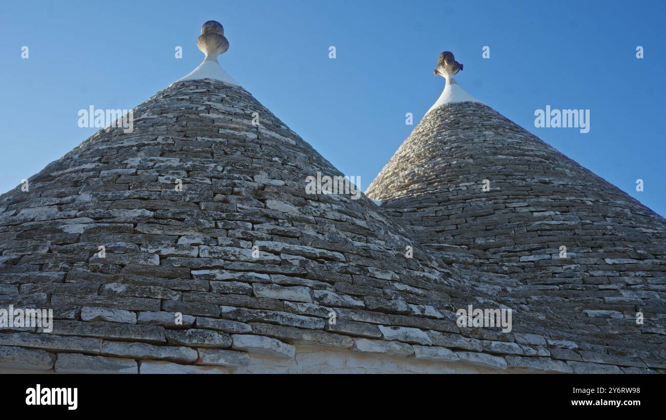 Historic stone trulli houses with conical roofs under a clear blue sky ...