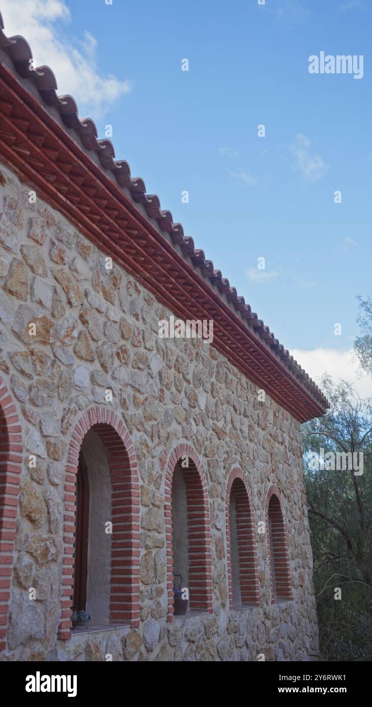 A mediterranean stone building featuring arched windows and a red tiled ...