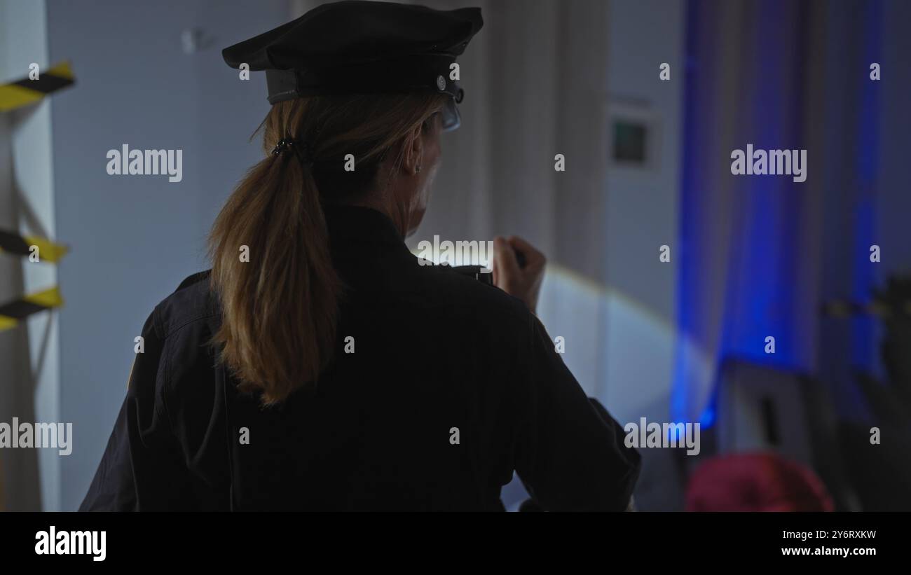 Back view of a blonde woman officer investigating an indoor crime scene ...
