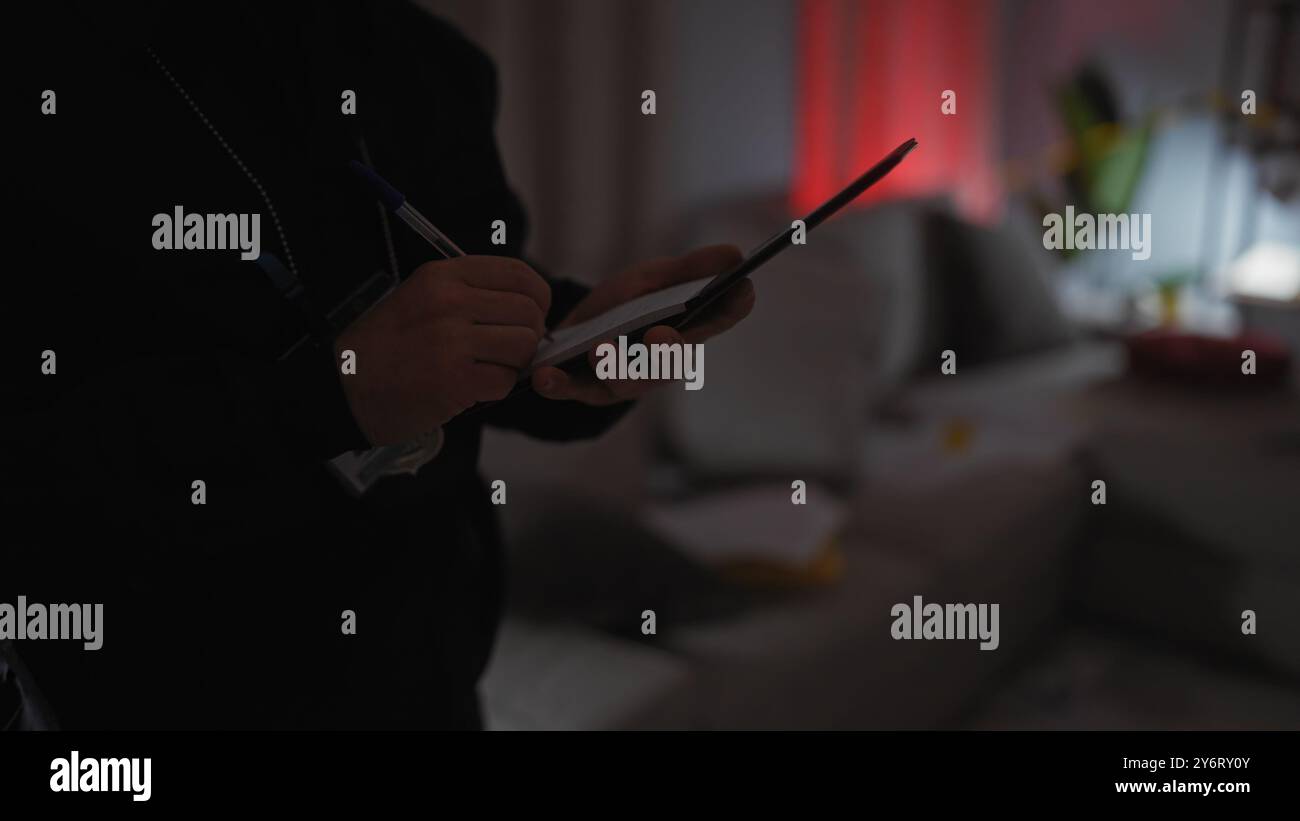 Young man taking notes during a crime scene investigation in a dark ...
