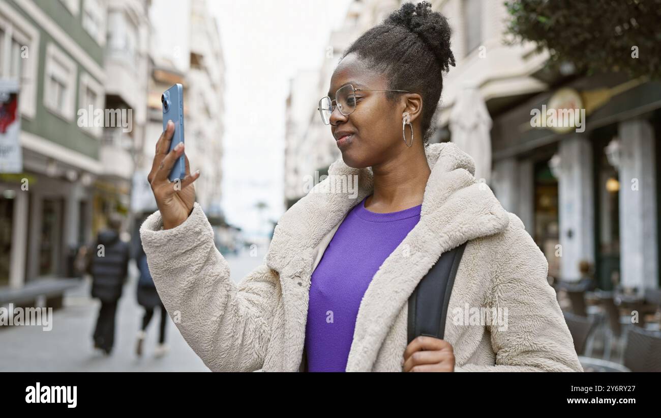 A young african american woman captures a selfie on her phone in a ...