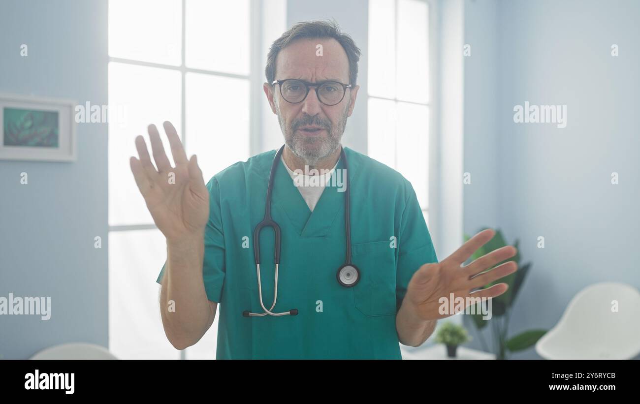 A middle-aged hispanic man in scrubs with a stethoscope gestures inside ...