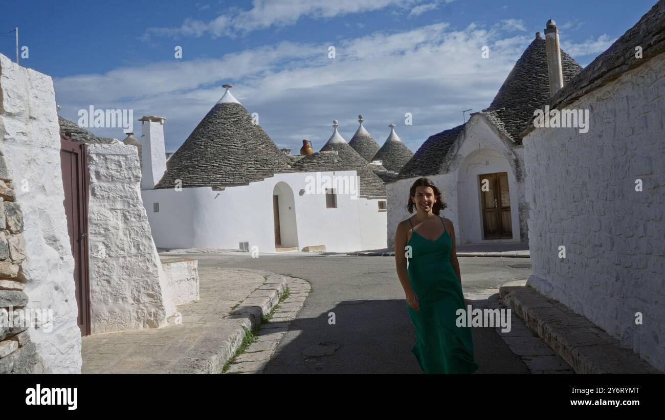 A beautiful young hispanic woman in a green dress walks down a street ...