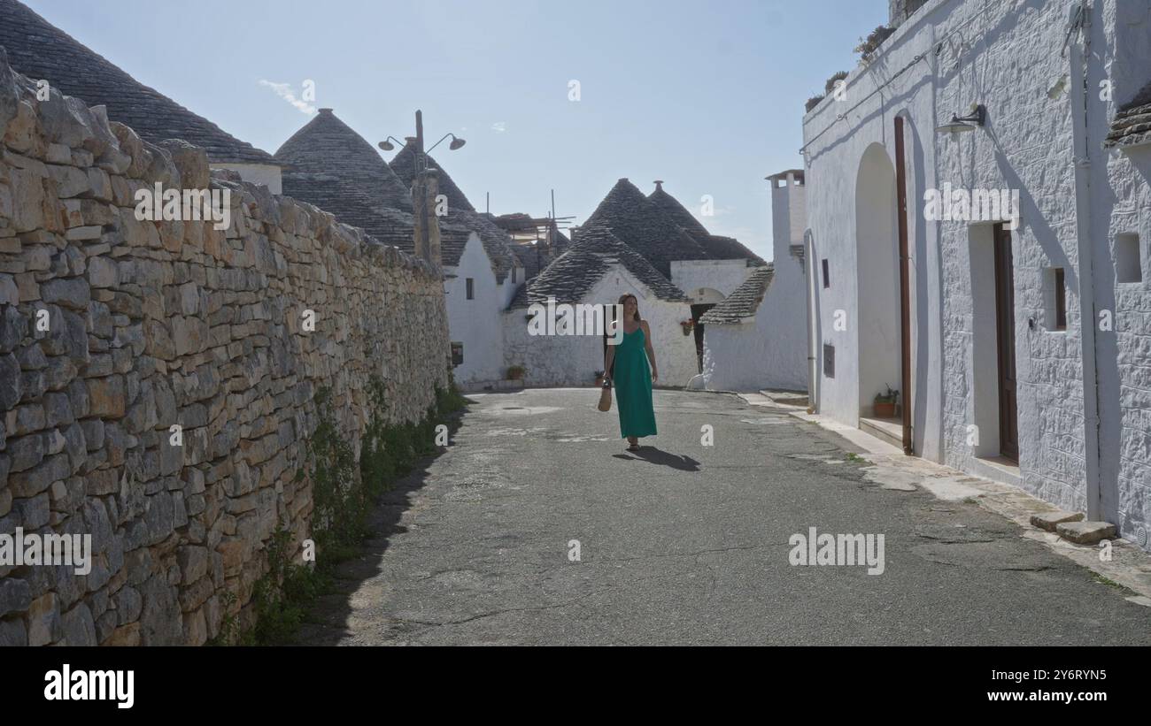 A beautiful young hispanic woman in a green dress walks along a quaint ...
