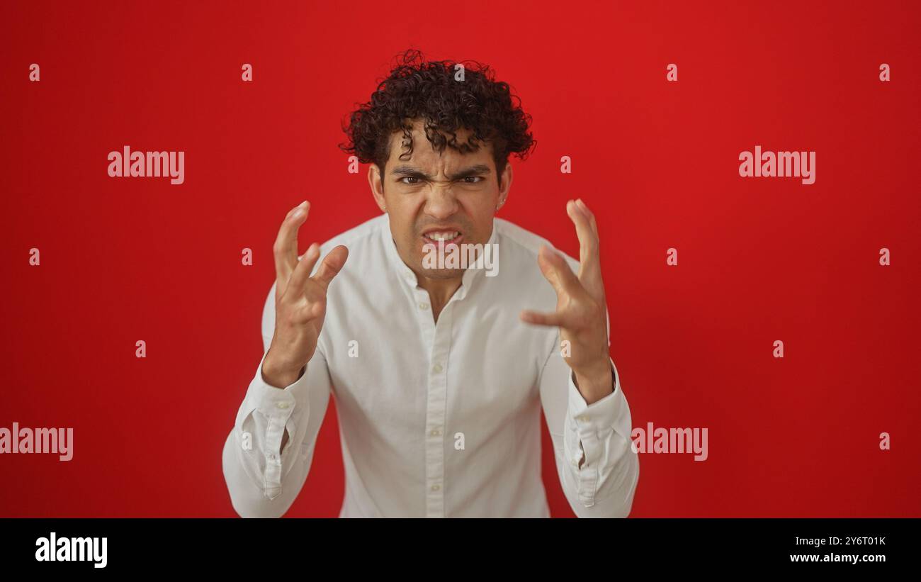 A frustrated young hispanic man in a white shirt expressing anger ...