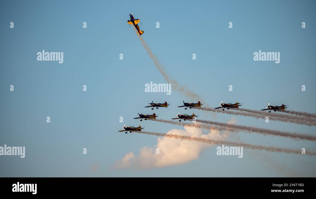 Stunt planes performing acrobatic maneuvers against a clear blue sky ...