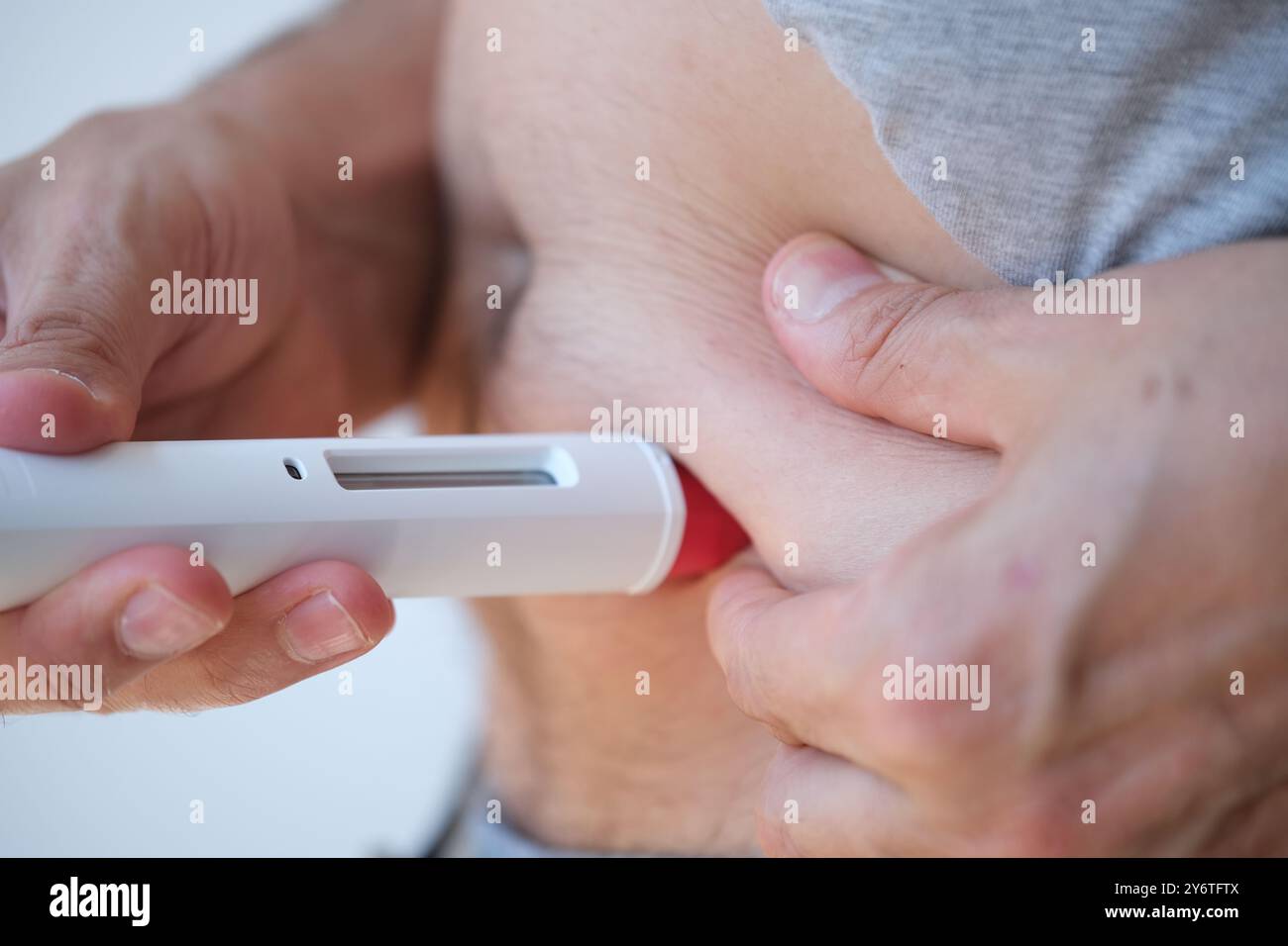 Detail of a man injecting himself in the abdominal area with a ...