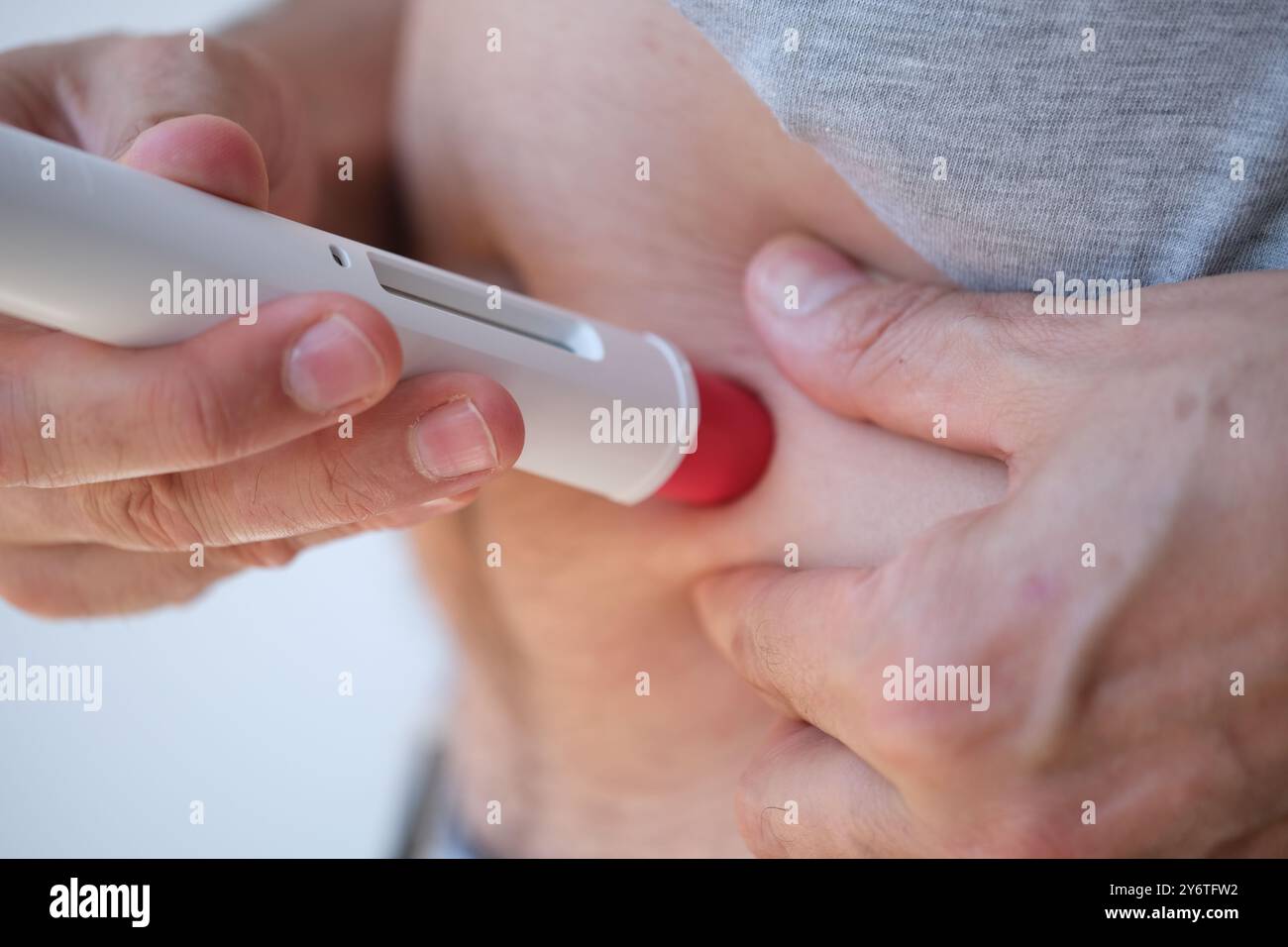 Detail of a man injecting himself in the abdominal area with a ...
