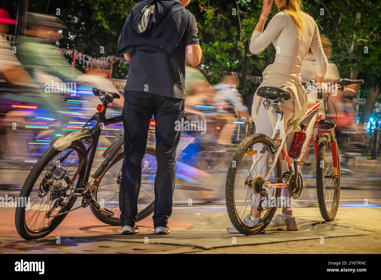 Couple enjoying a vibrant evening bike ride in a lively urban ...