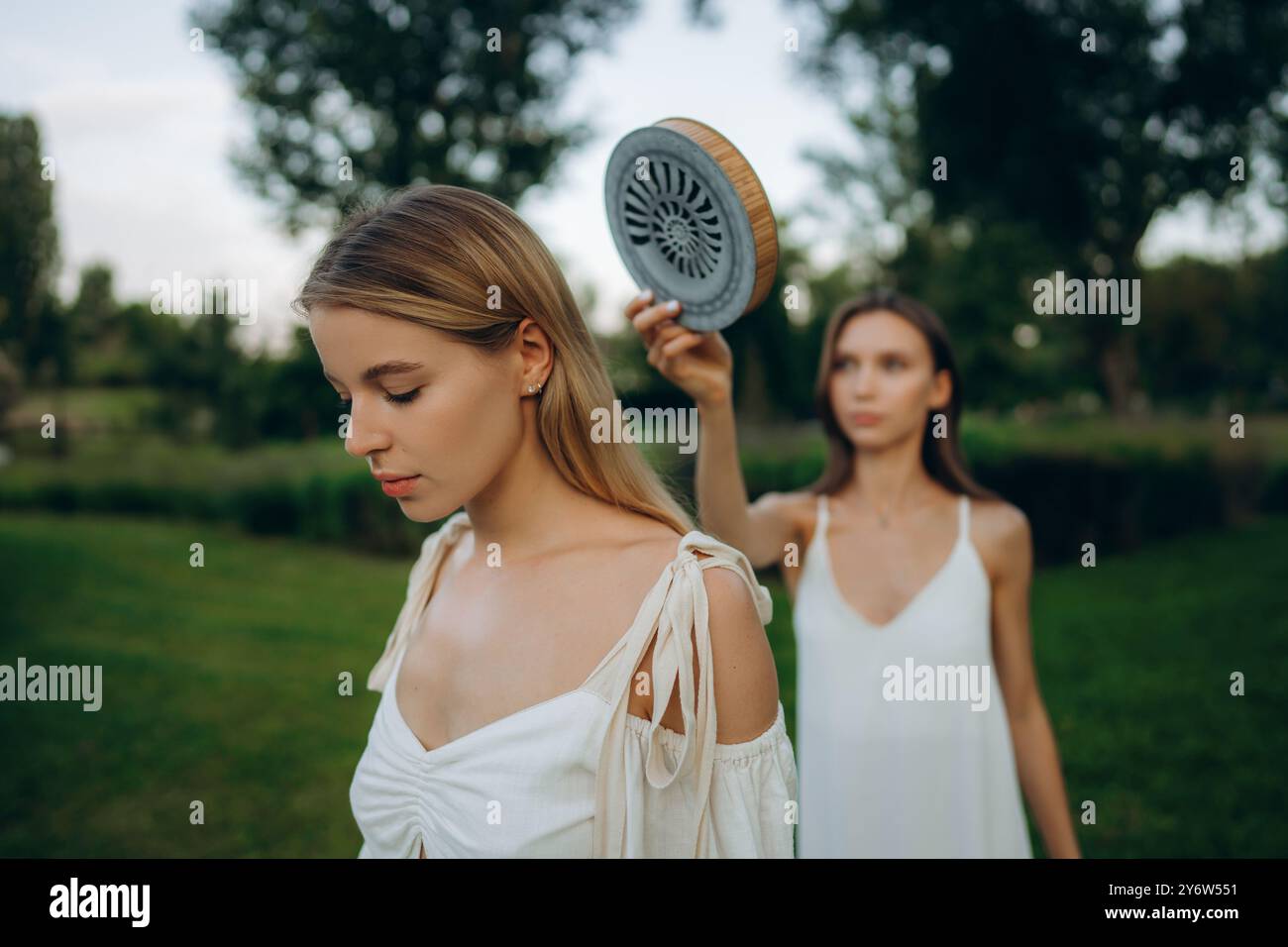 Two women in a garden during daytime with one holding a unique object ...
