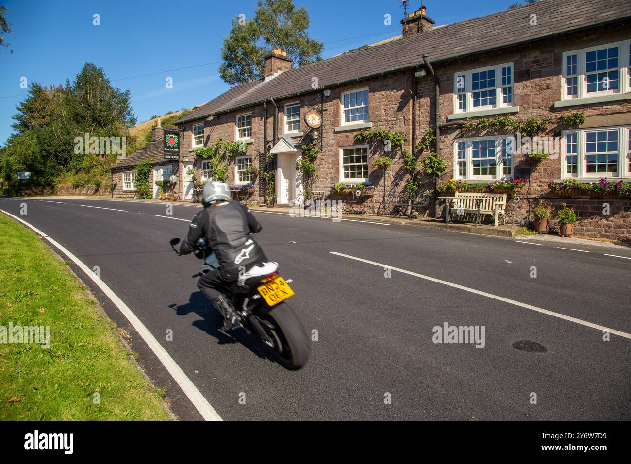 Motorcyclist biker riding past the Rose and Crown country coaching inn ...