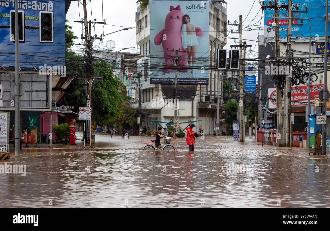 A woman seen pushing a bicycle through a heavily flooded street at Sang ...