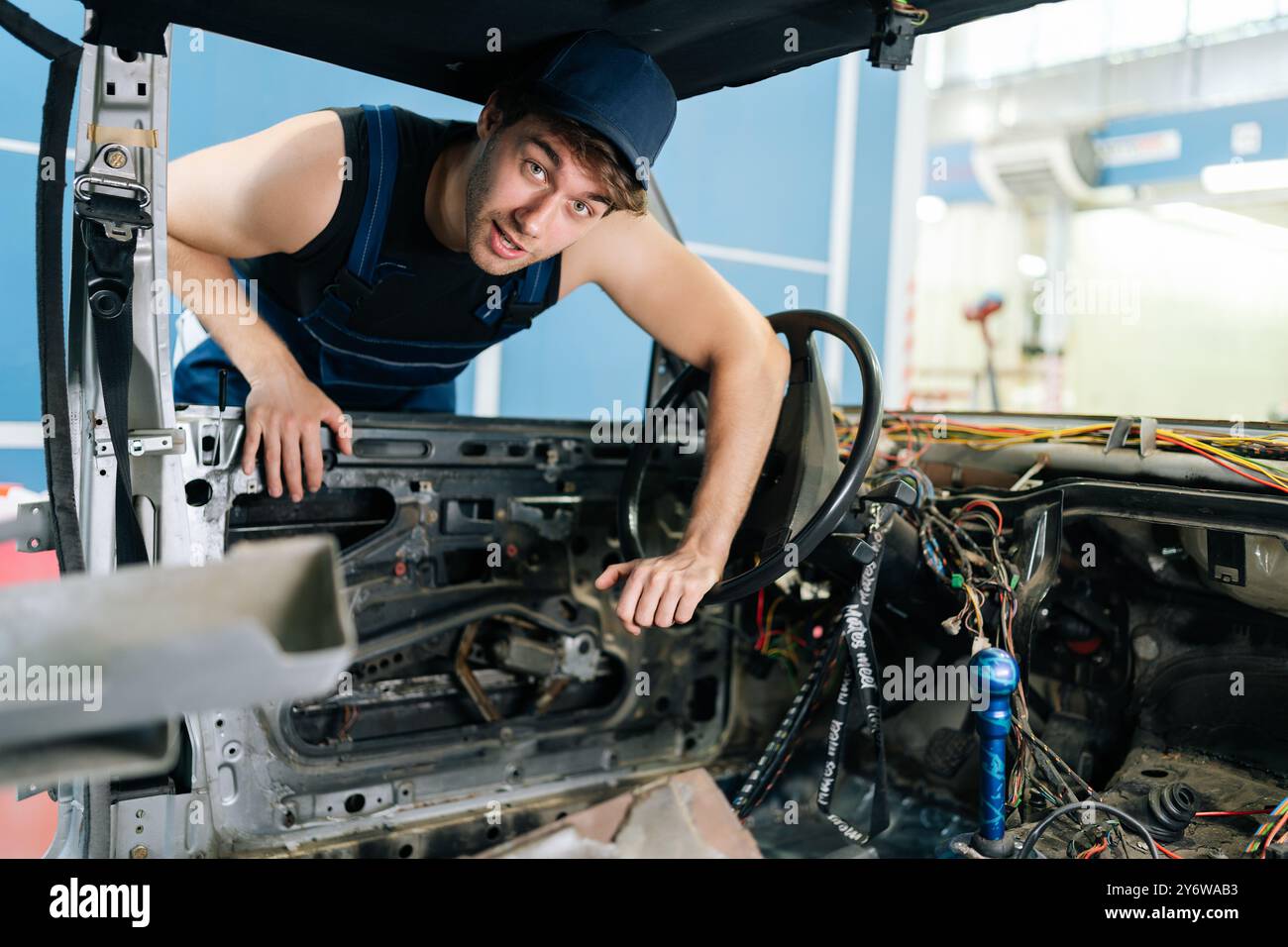 Portrait from interior of old vehicle to skilled mechanic in overalls ...