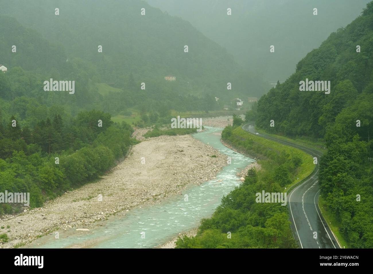 A gentle river flows through verdant hills, shrouded in soft mist ...