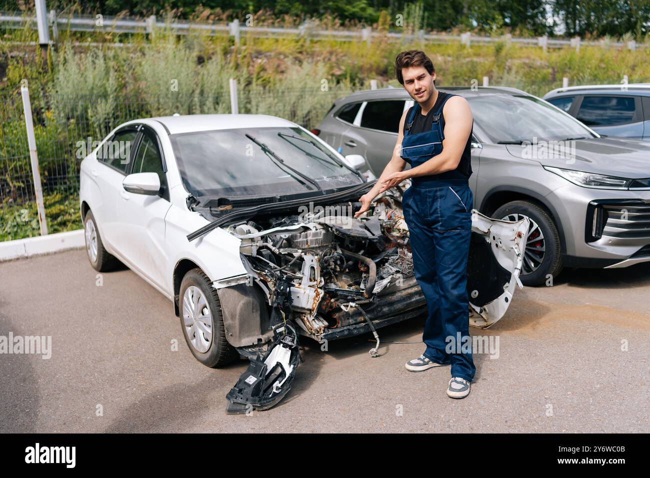 Serious mechanic assessing damage to white car that has been severely ...