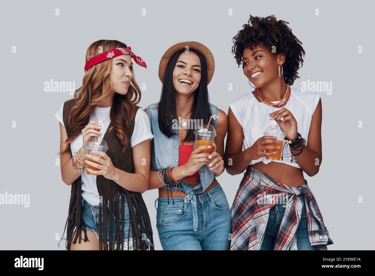 Three attractive young women drinking refreshing cocktail and smiling ...