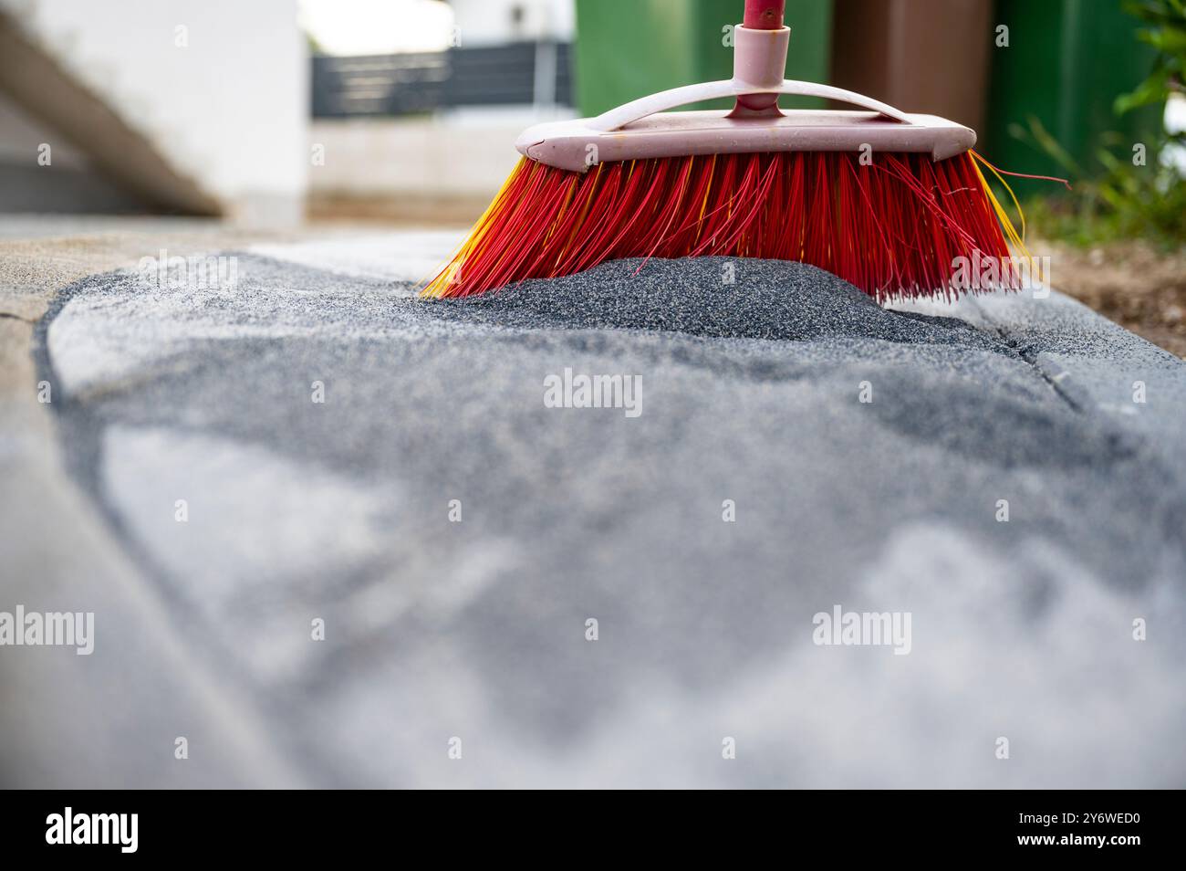 Low angle view of a broom brushing filling sand into the gaps between ...